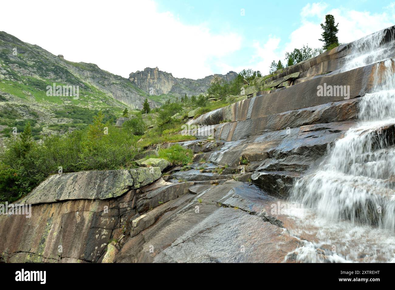 Steep stone steps from which a rapid waterfall cascades down in a ...