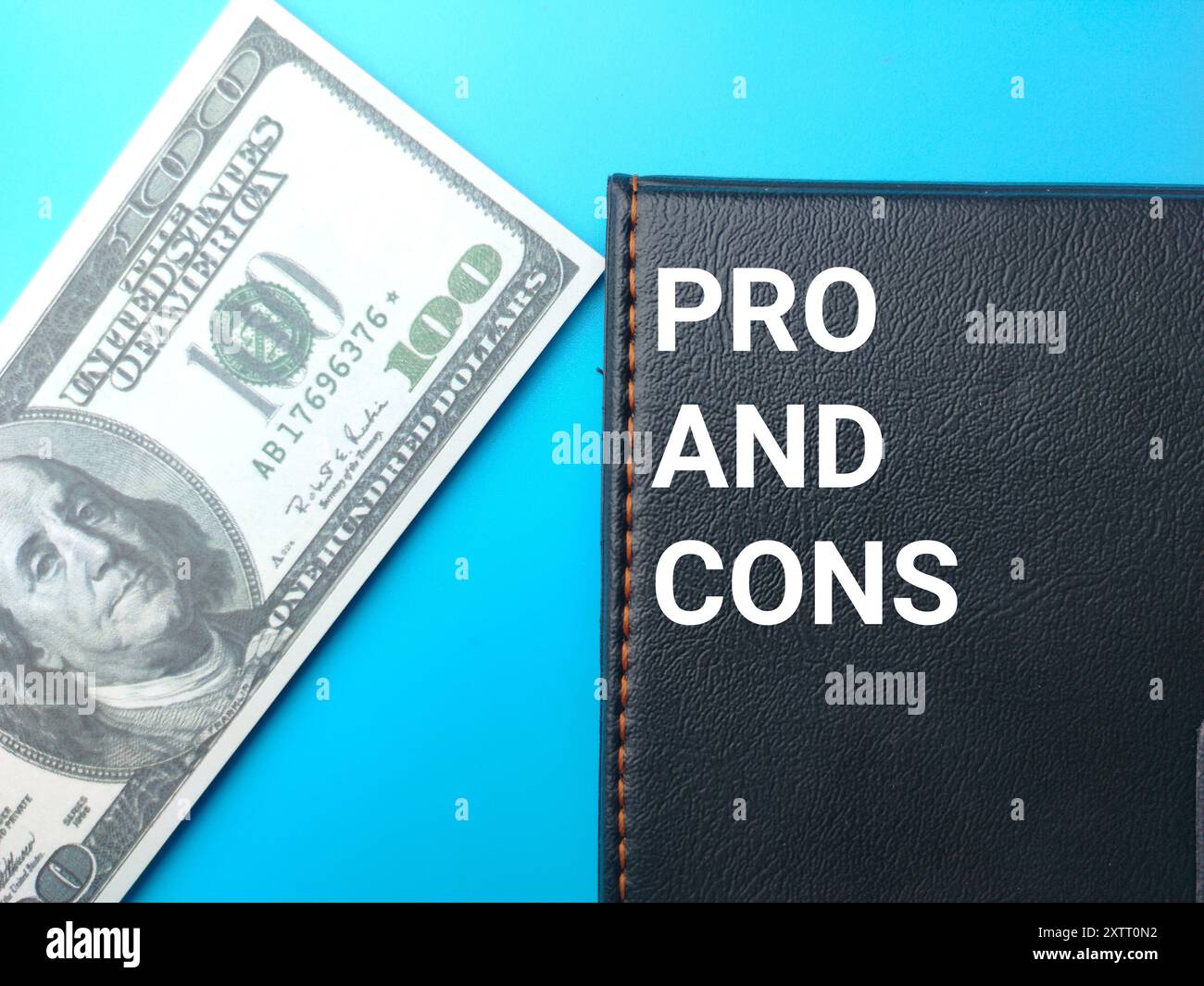 Banknote and notebook with word PRO AND CONS on a blue background ...