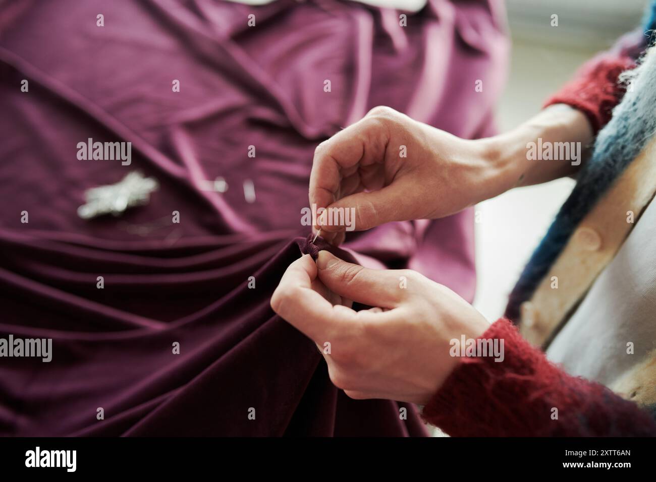 High angle of hands of young unrecognizable male couturier pinning ...