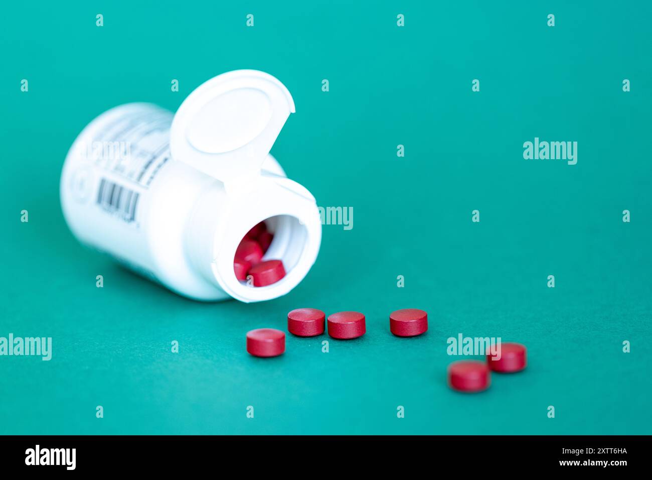 jar of pills and a handful of red round pills on a dark green ...