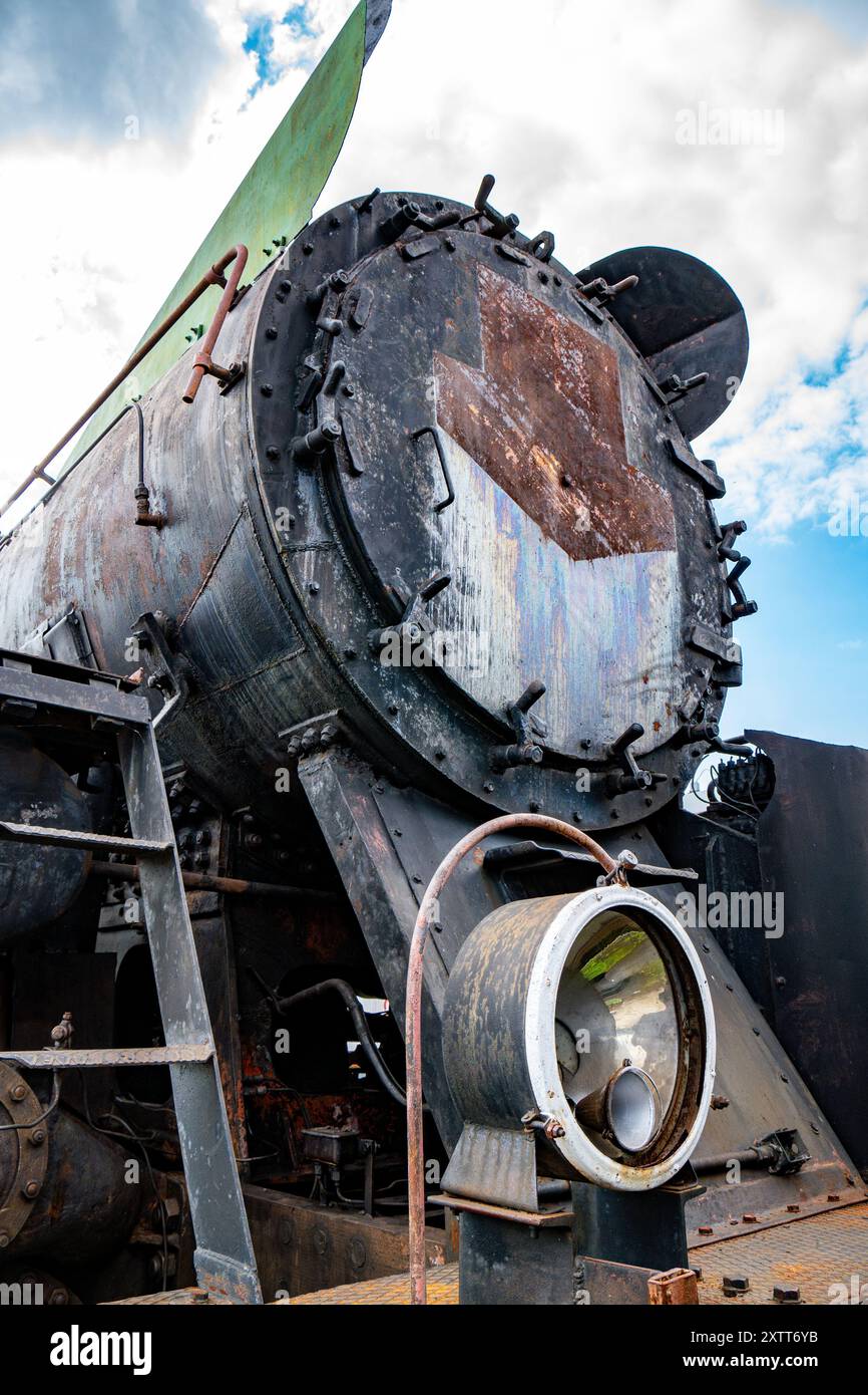Details of an old rusty steam train in a railway yard under a cloudy ...