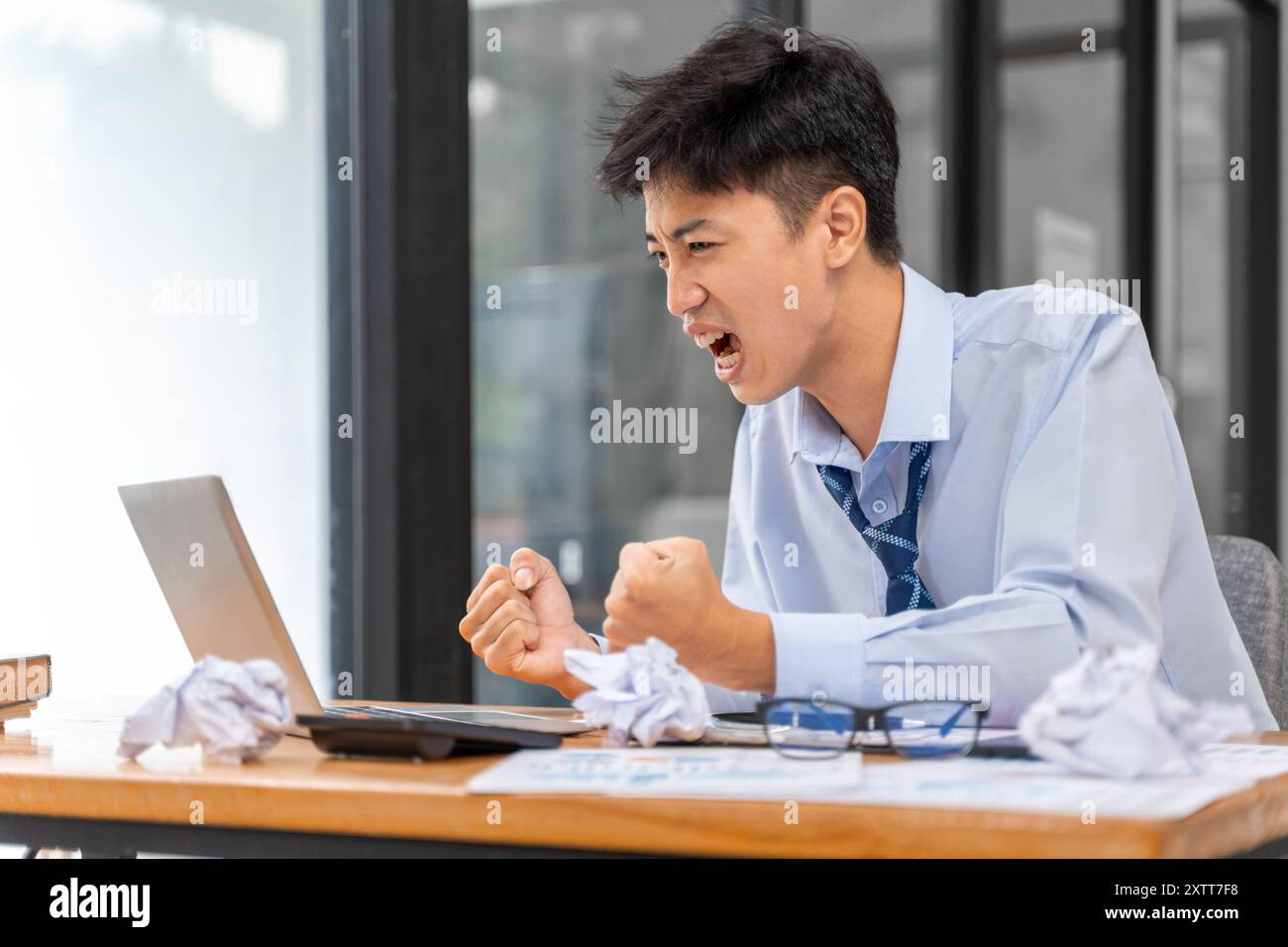 Frustrated and angry young businessman working late at the office ...