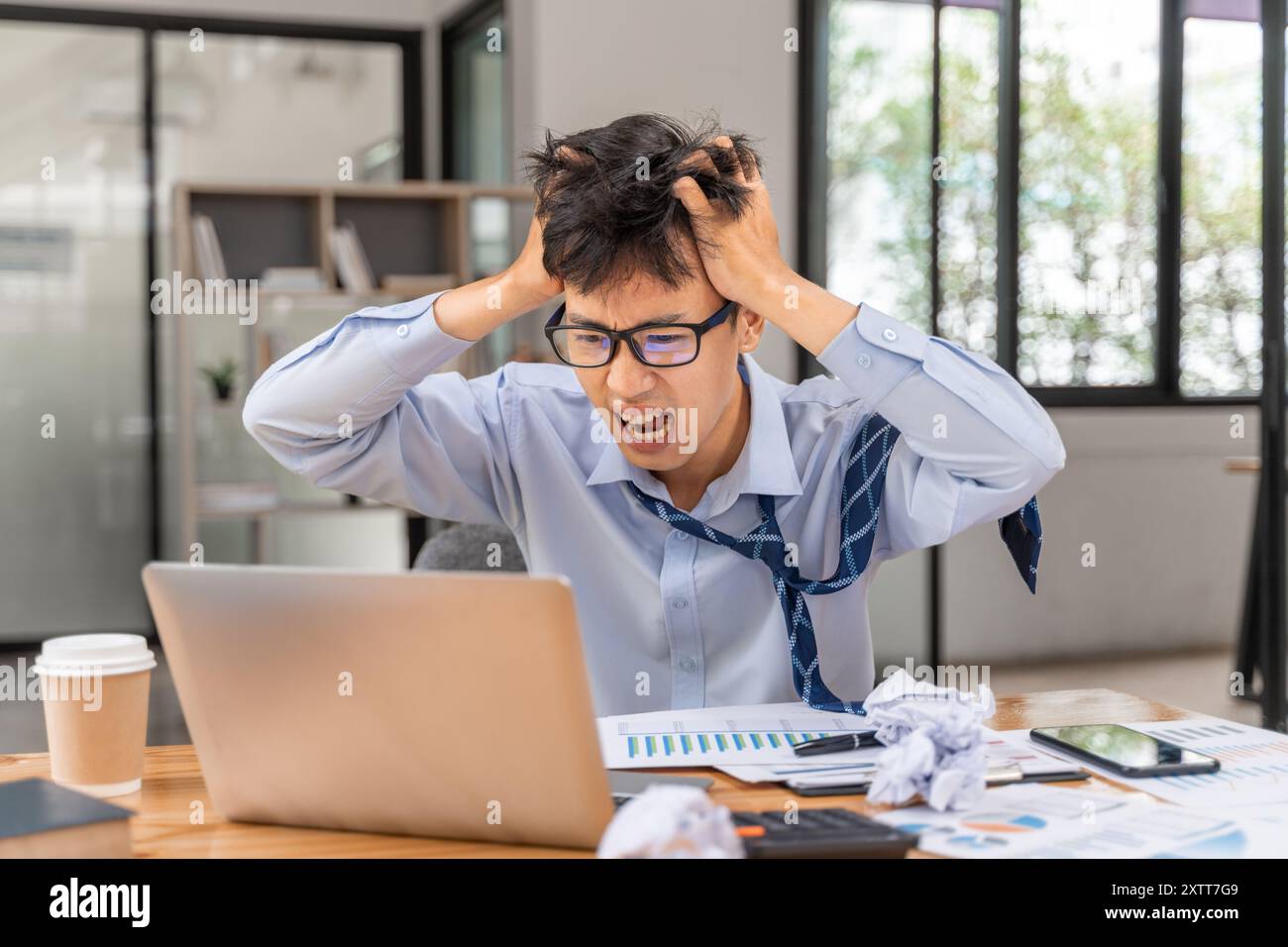 Frustrated and angry young businessman working late at the office ...