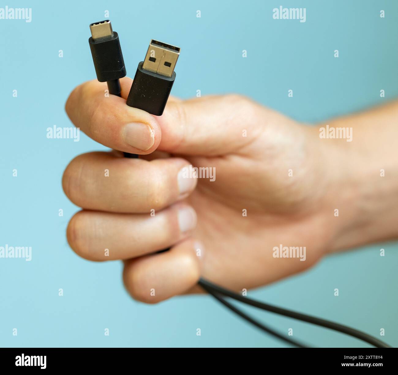 man holds several cables in hand, different types of USB cables ...