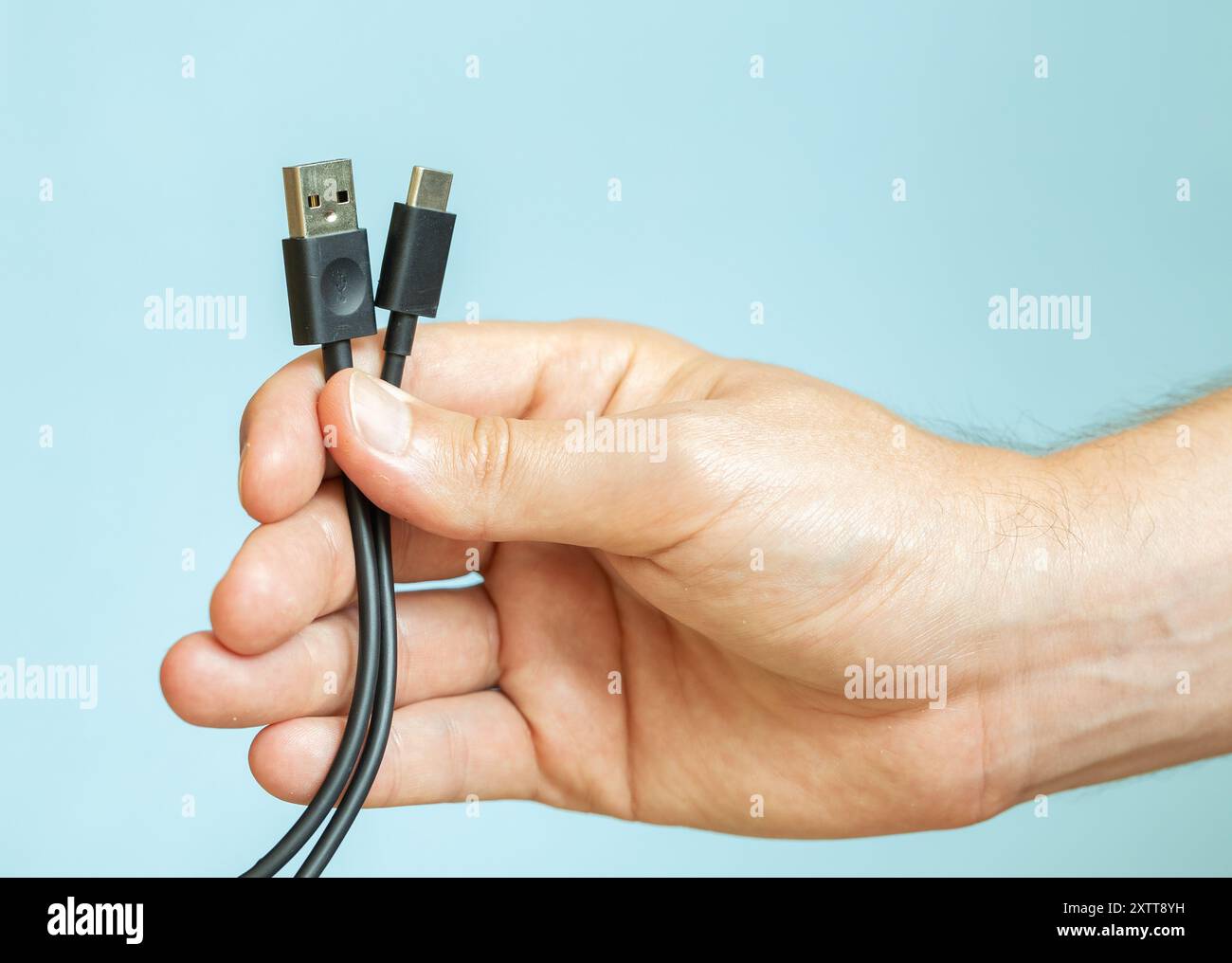 man holds several cables in hand, different types of USB cables ...
