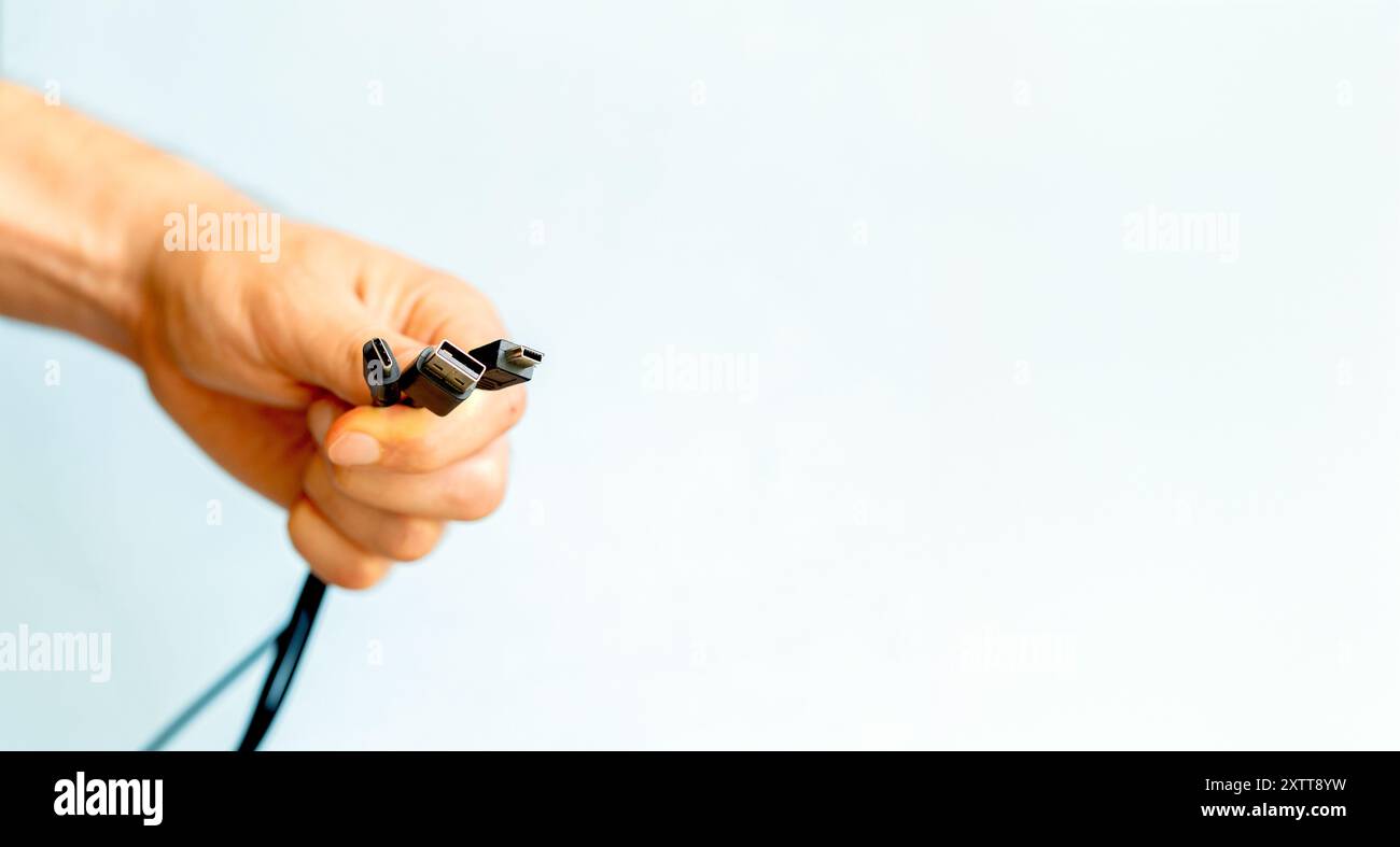 man holds several cables in hand, different types of USB cables ...