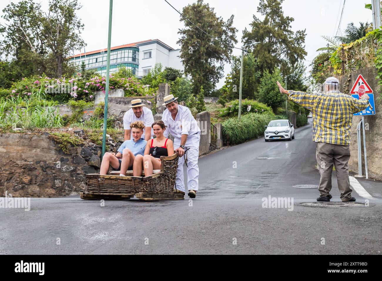 A man with a stop sign halts traffic as a wicker toboggan slides down ...
