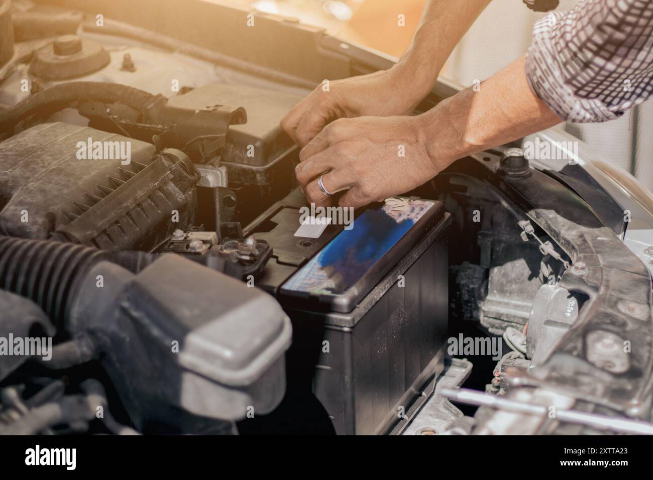 Close up of car mechanic hands checking the battery of a car. A man is ...