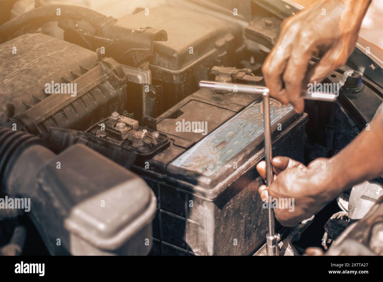 An automotive technician disassembles an old battery in a car with a ...