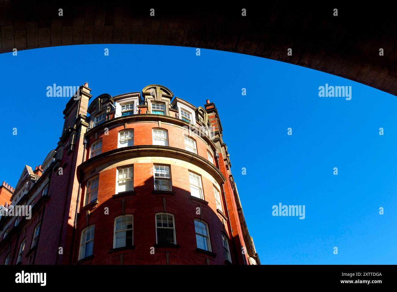 A red brick building with multiple windows and a curved facade under a ...