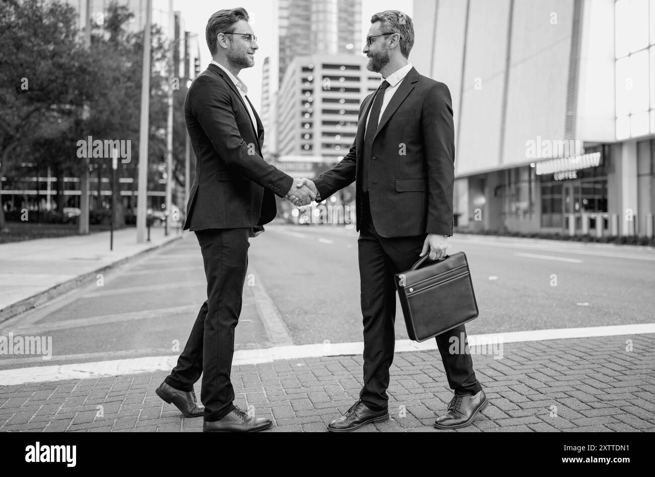Business men shaking hands outdoors Black and White Stock Photos ...