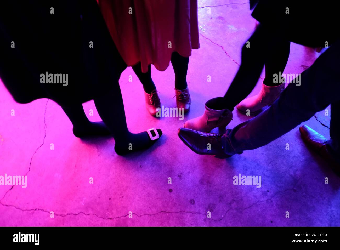 Legs and shoes of four women in conversation at an event with coloured ...
