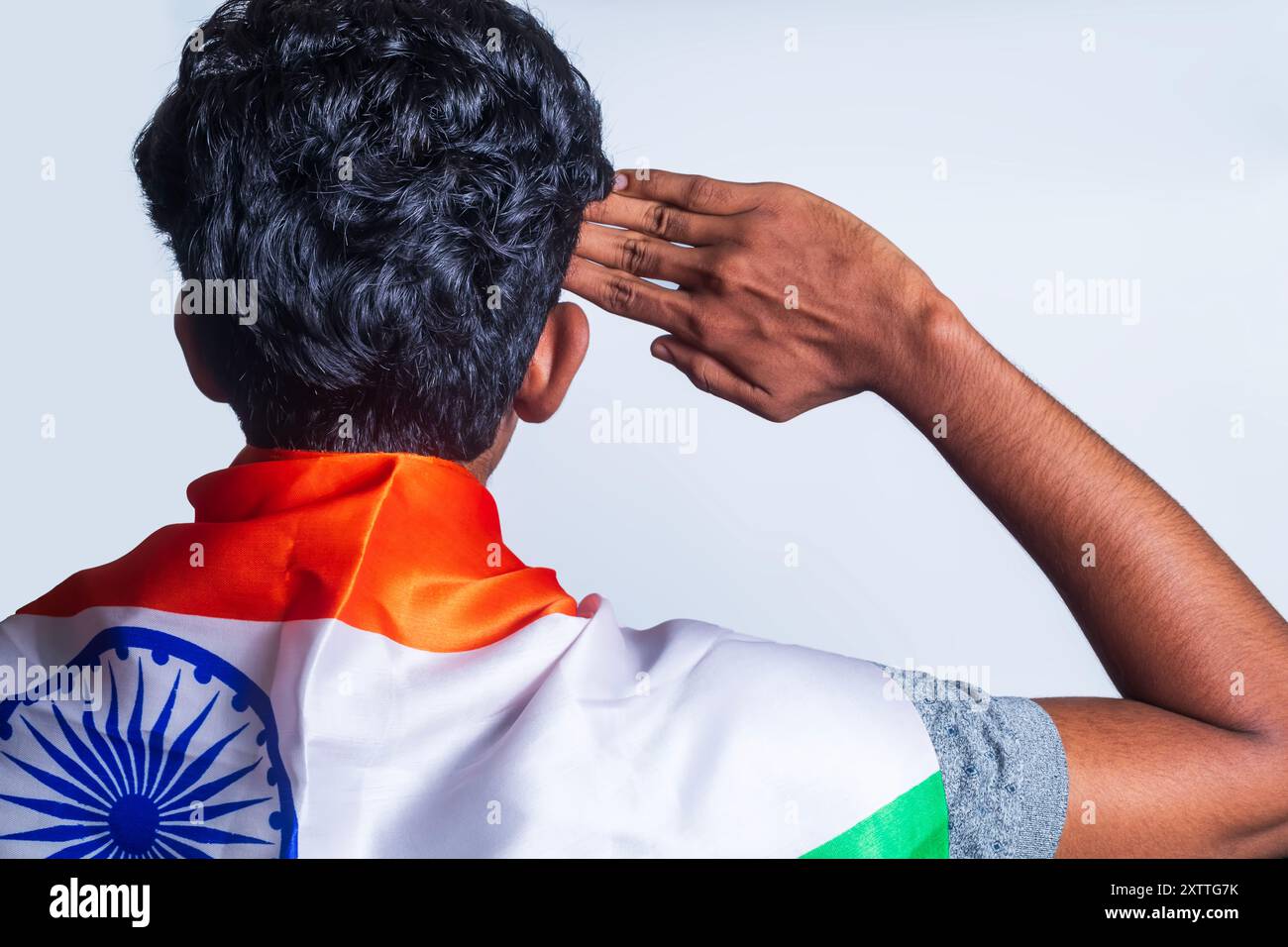 A young person saluting with an Indian flag draped over their shoulder ...