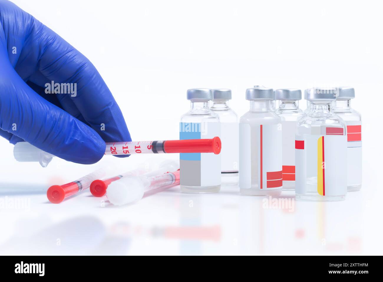 Blue gloved doctor holding syringe and stack of syringes lying with ...