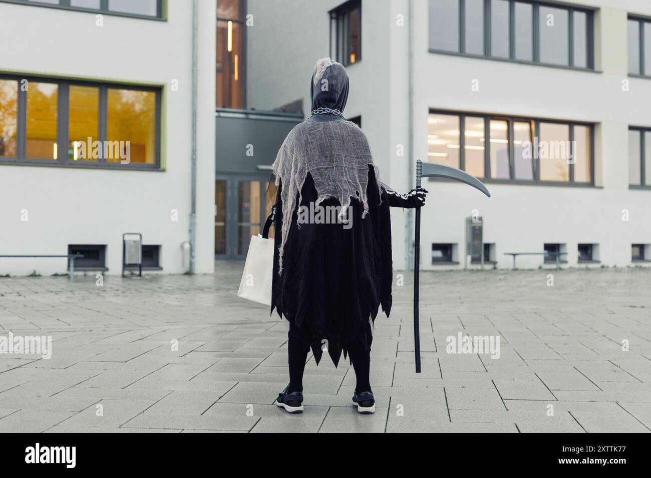 Back view of kid in grim reaper Halloween costume with scythe and bag ...