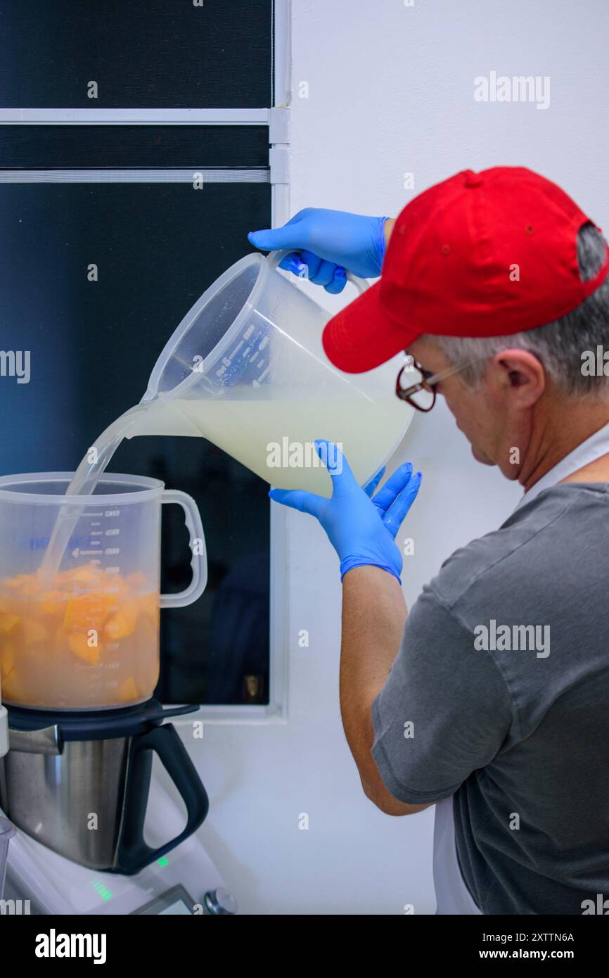 Chef pouring liquid into blender with chopped fruit Stock Photo - Alamy