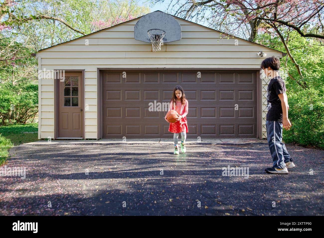 Two children play driveway basketball together in spring Stock Photo ...