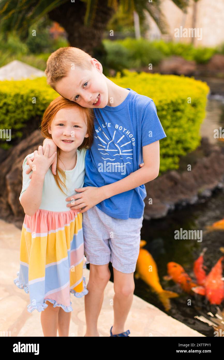Brother and Sister hugging by koi pond Stock Photo - Alamy