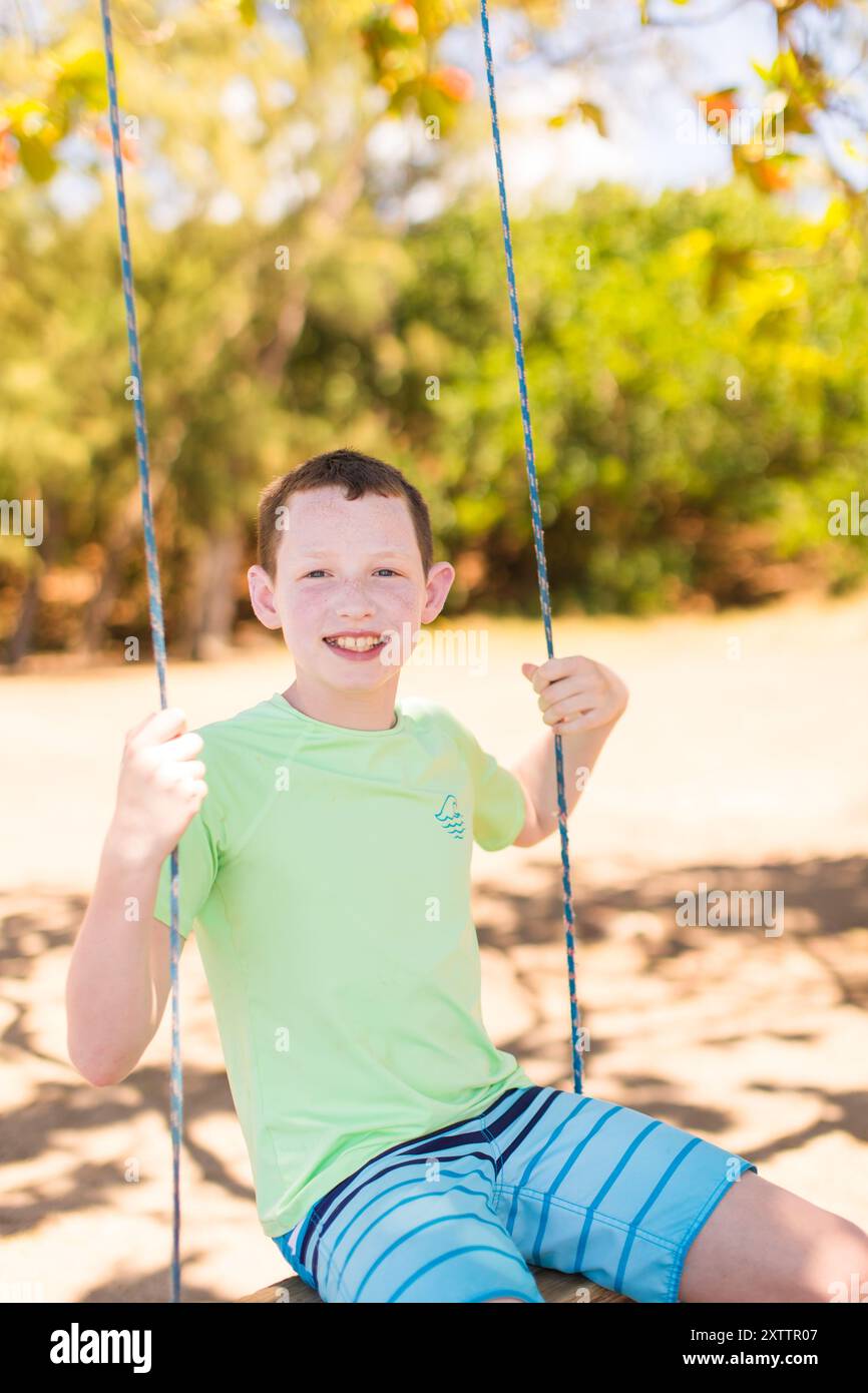 Teenage boy sitting on a rope swing Stock Photo - Alamy