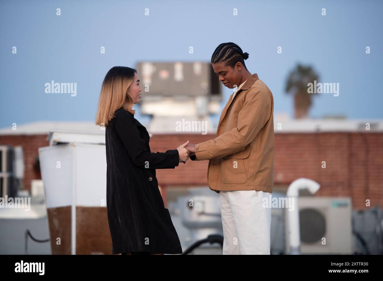 Multi racial couple holding hands and sharing a moment on a roof Stock ...