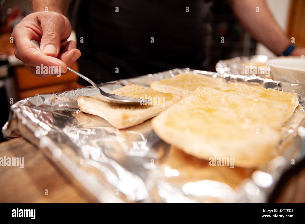 Close-up of a person spreading butter on bread slices using a spoon ...