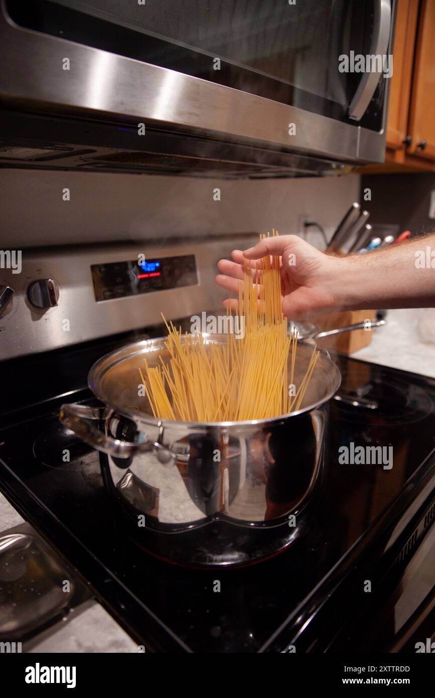 Placing spaghetti into a pot of boiling water Stock Photo - Alamy
