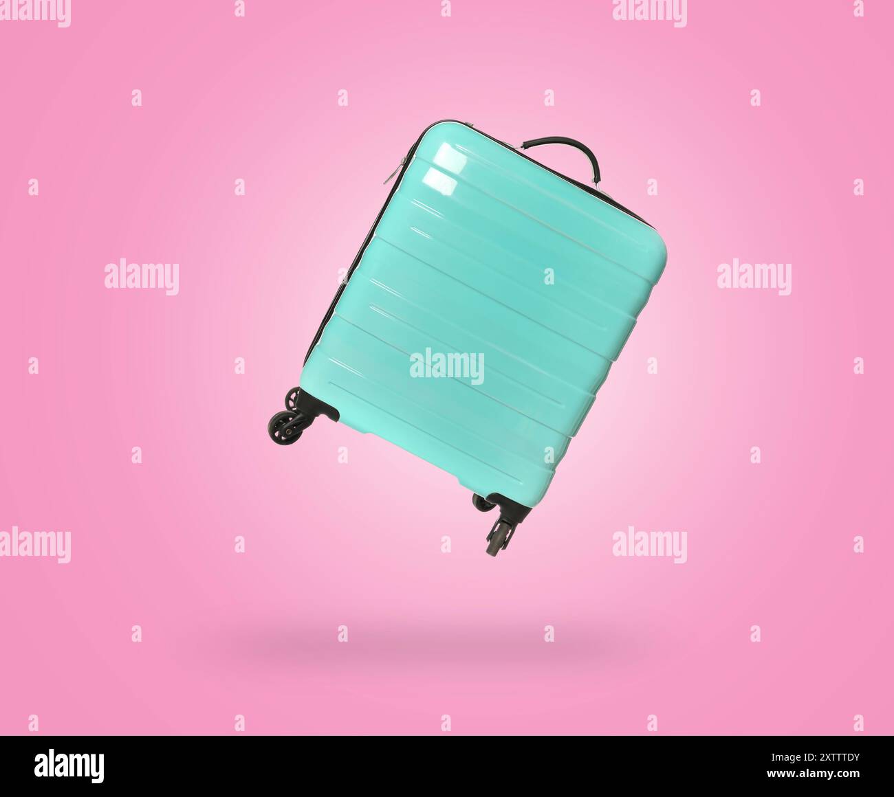Turquoise suitcase in air on pink background Stock Photo - Alamy