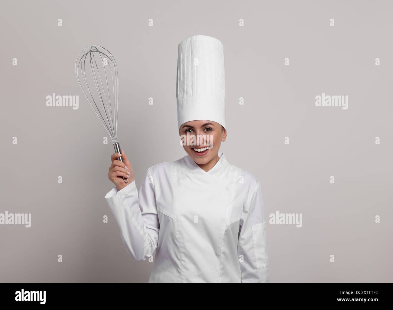 Happy pastry chef with big whisk on light grey background Stock Photo ...