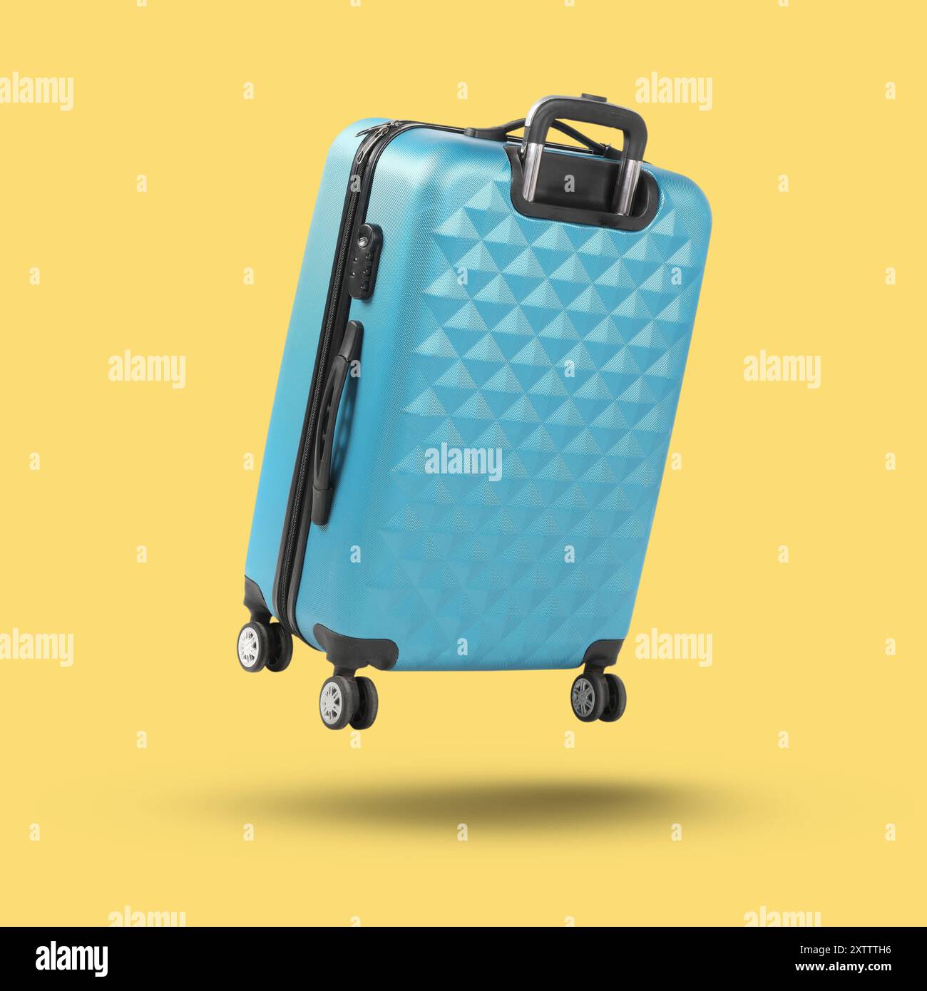 Light blue suitcase in air on yellow background Stock Photo - Alamy