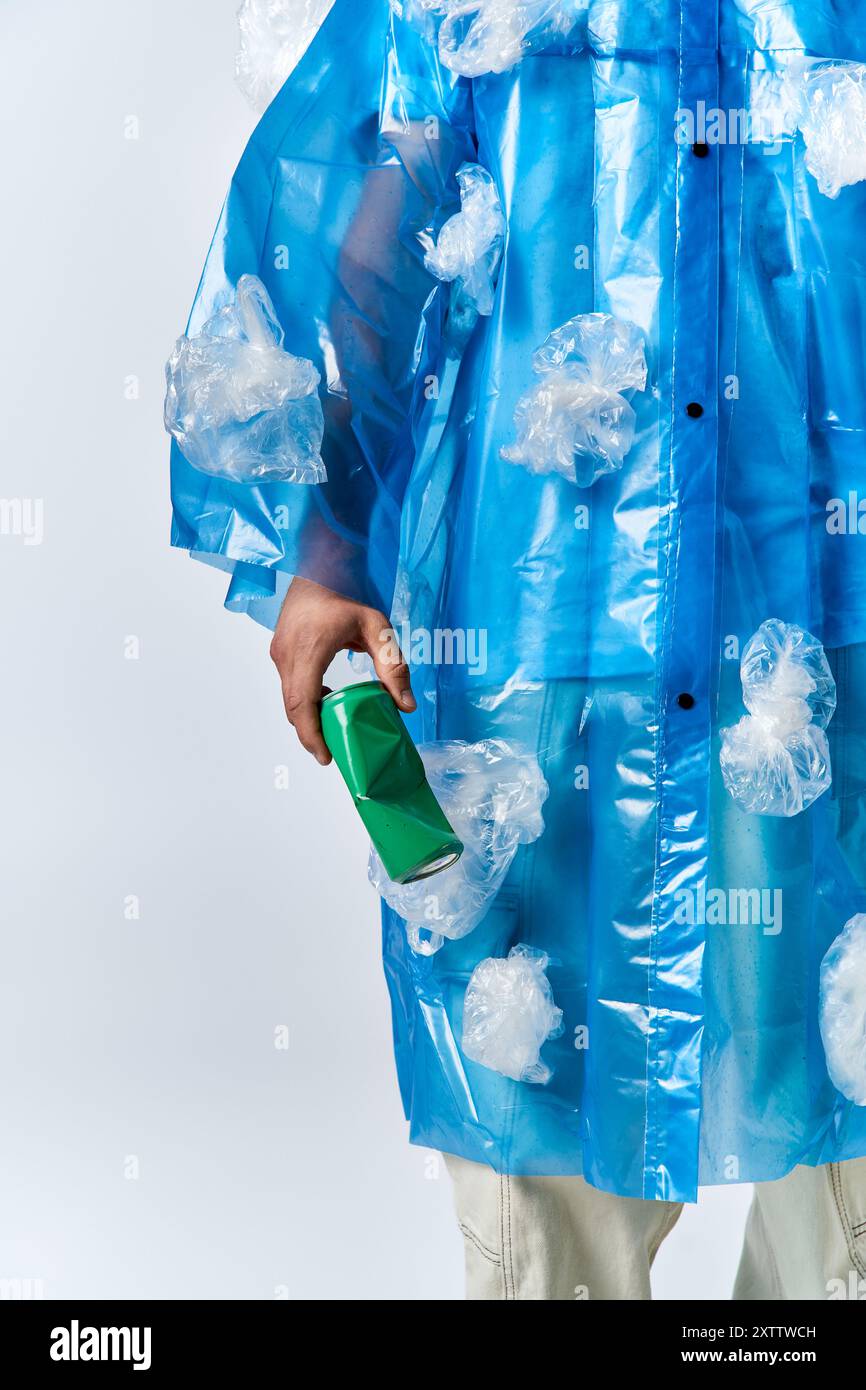 A man stands in a blue plastic garment, holding a green can Stock Photo ...