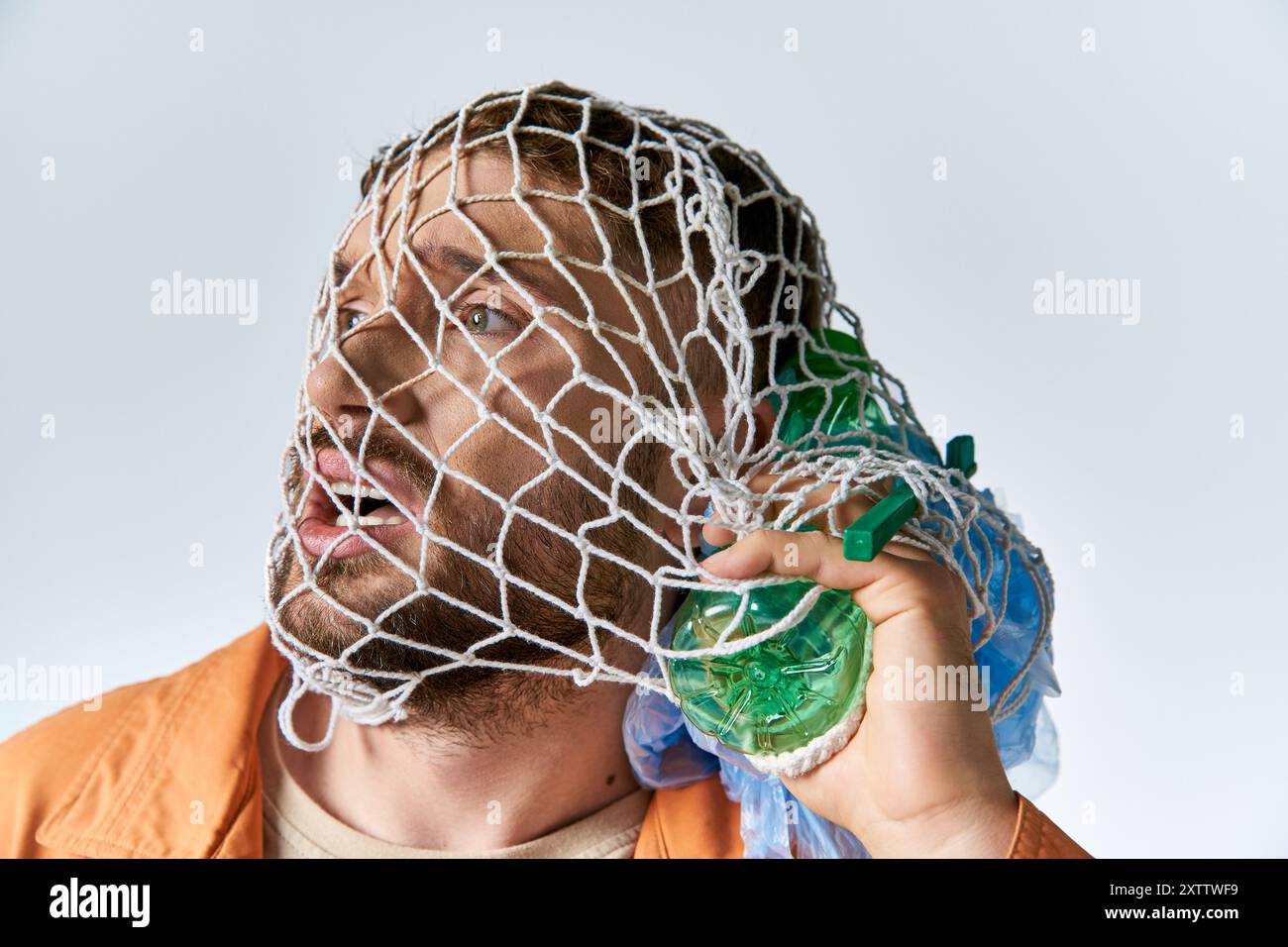A man struggles against a net of plastic, his face contorted in ...