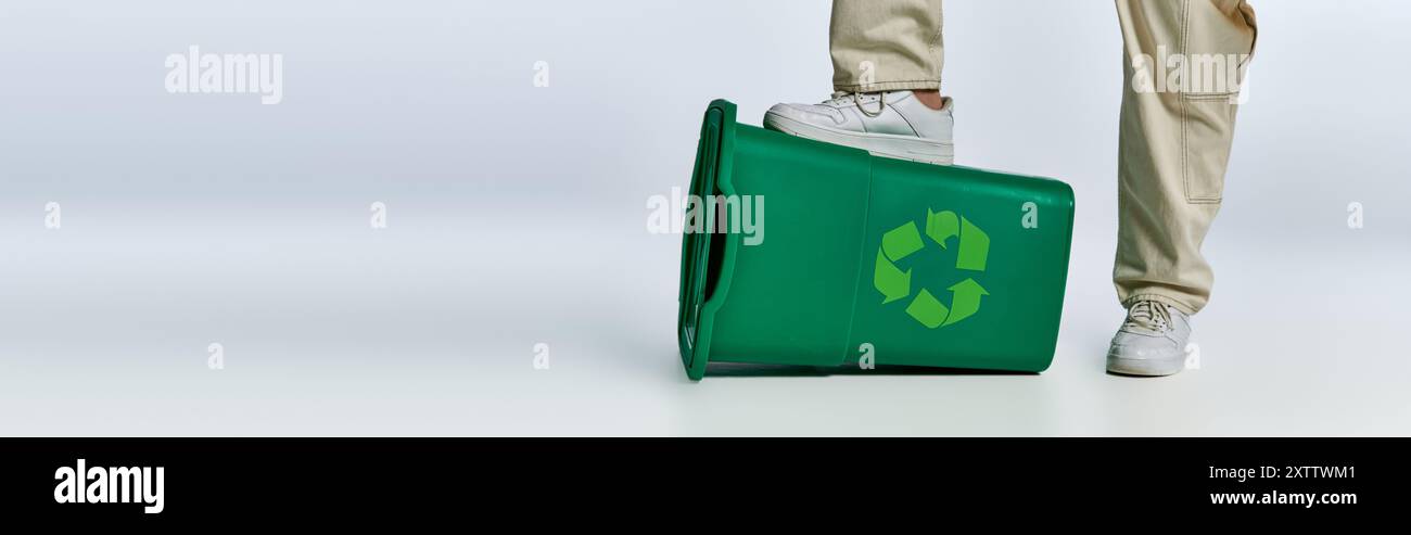 A man stands with one foot on a green recycling bin, leaving his mark ...