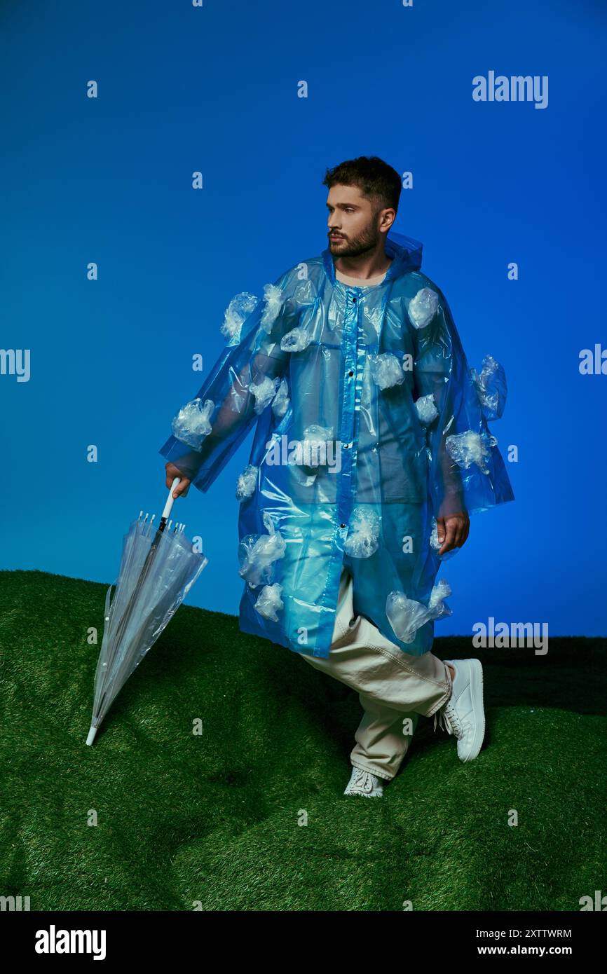 Man in plastic raincoat and umbrella stands on grass, with plastic bags ...