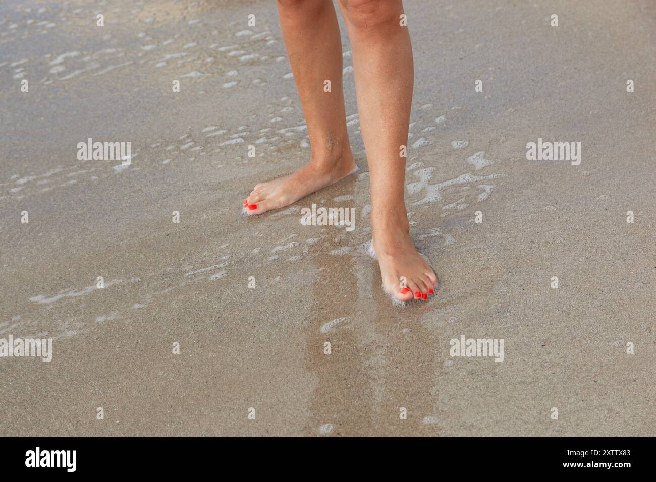 Female feet on beach sand. Woman's feet with red nails on seashore sand ...