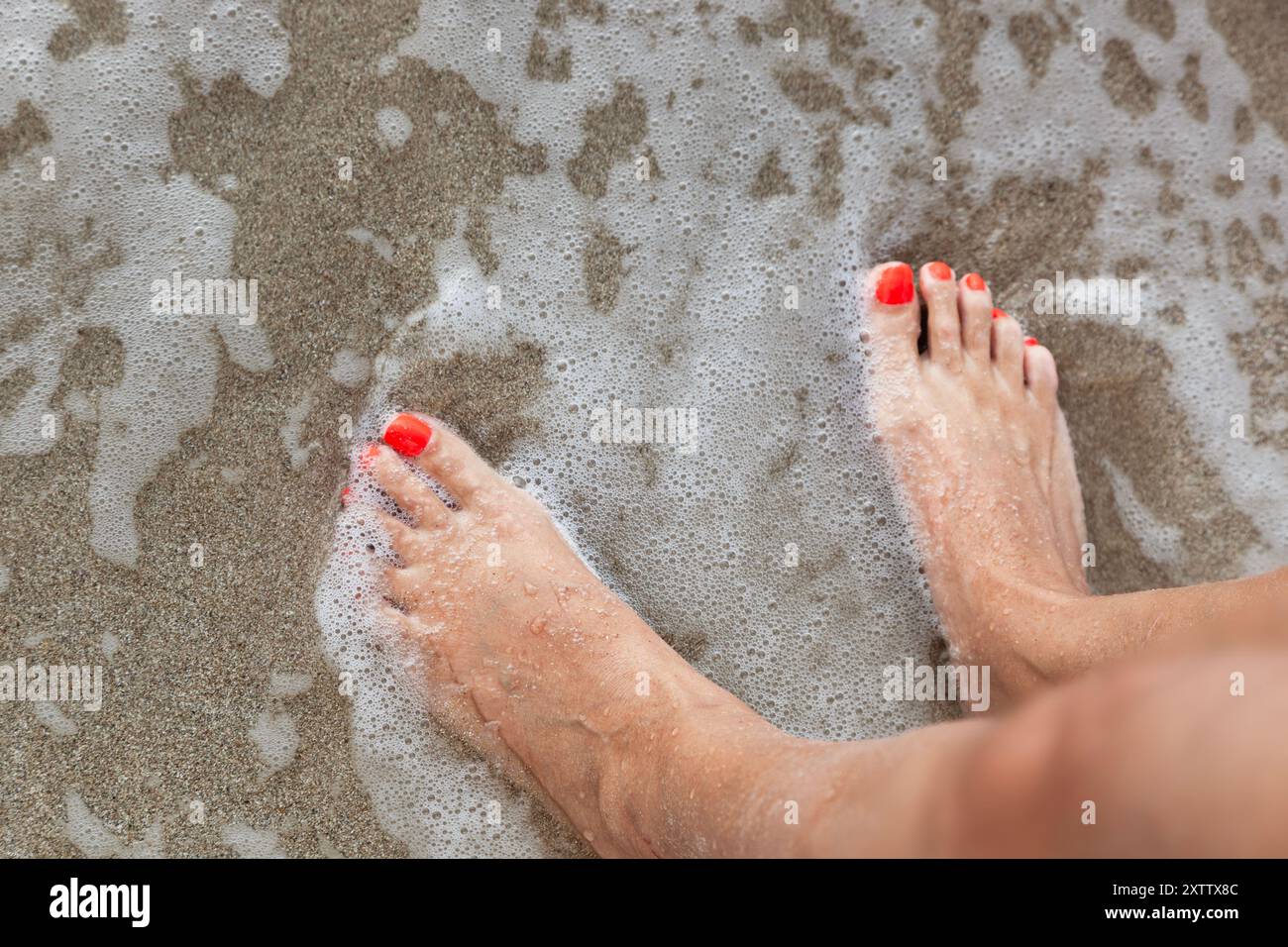 Female feet on beach sand. Woman's feet with red nails on seashore sand ...