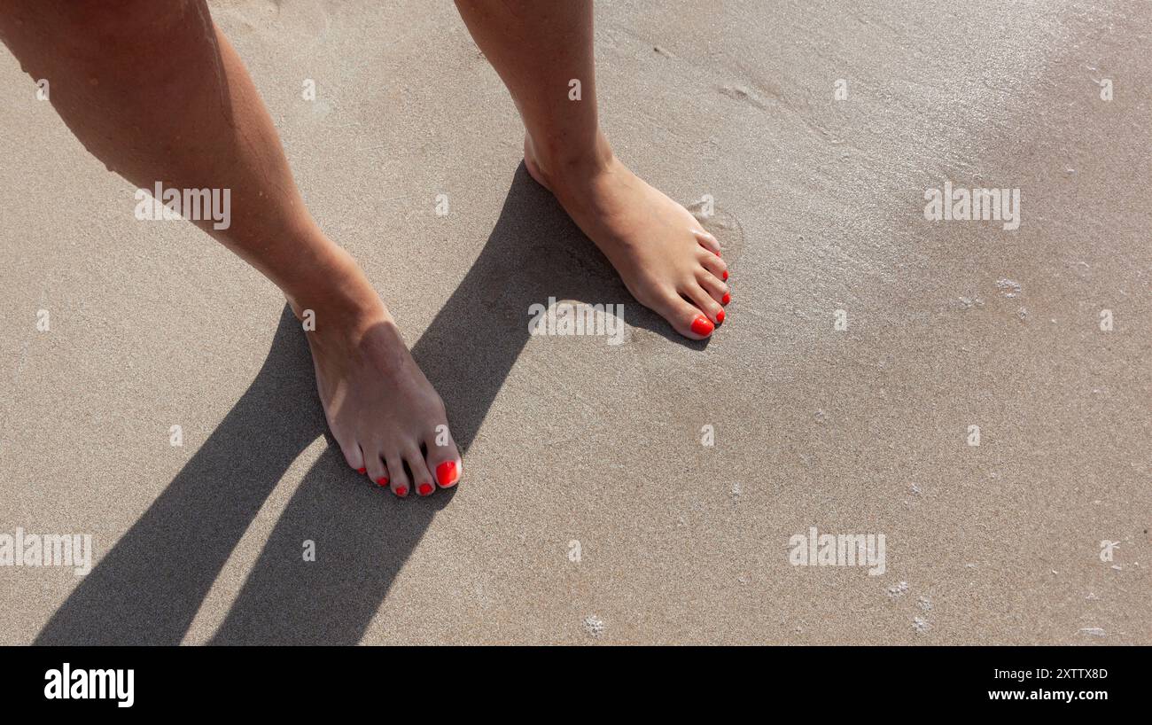 Female feet on beach sand. Woman's feet with red nails on seashore sand ...