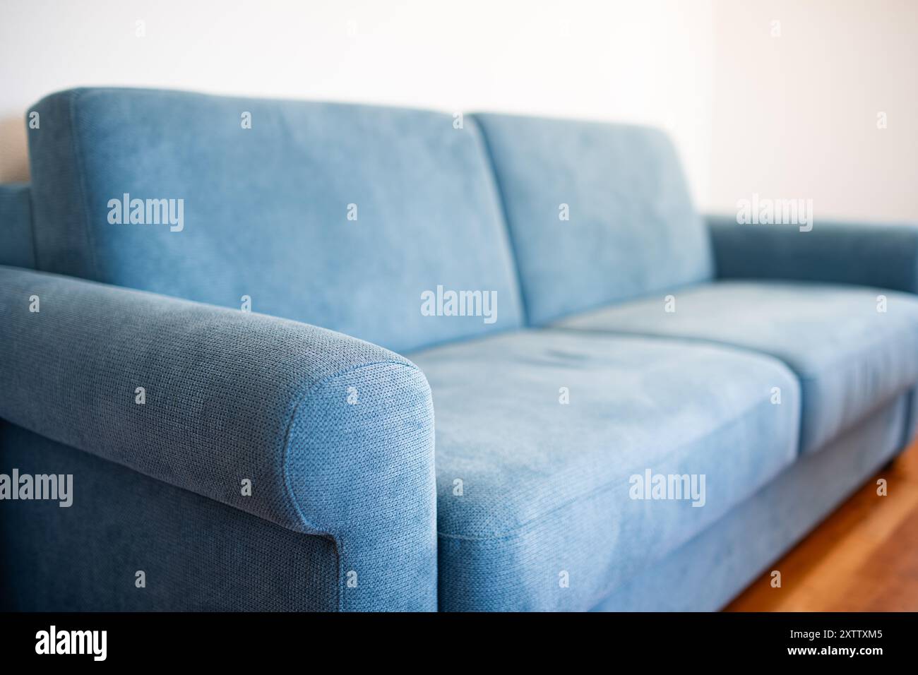 Light blue fabric sofa with inside apartment room. Close up, side view ...