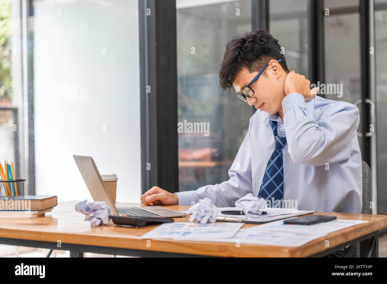 Tired and overworked young businessman using his hand to massage his ...