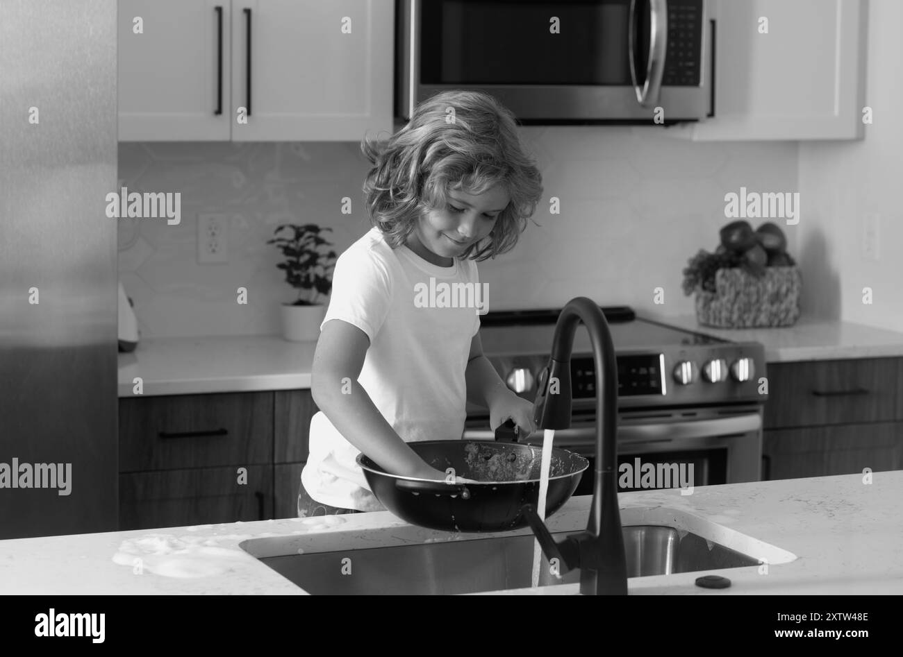 Home chores. Kid in kitchen cleaning plates. Cute boy washing dishes in ...