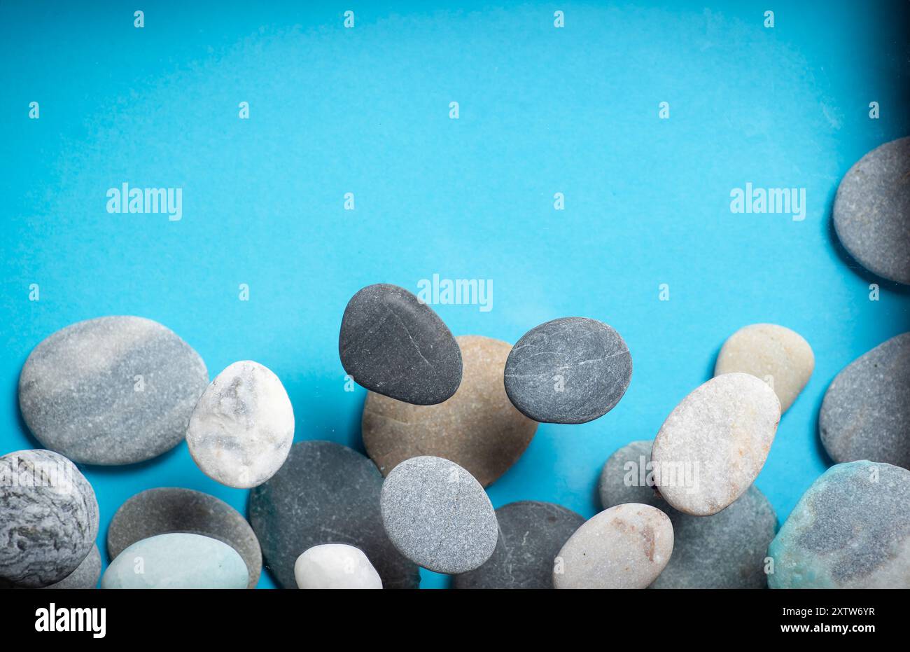 Small stones of different shapes, colors and sizes on a blue background ...