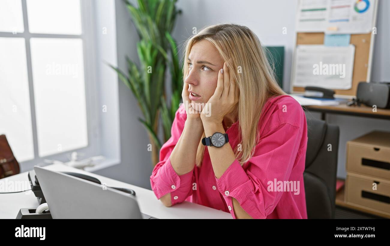 A stressed young woman at her workplace showing frustration in an ...