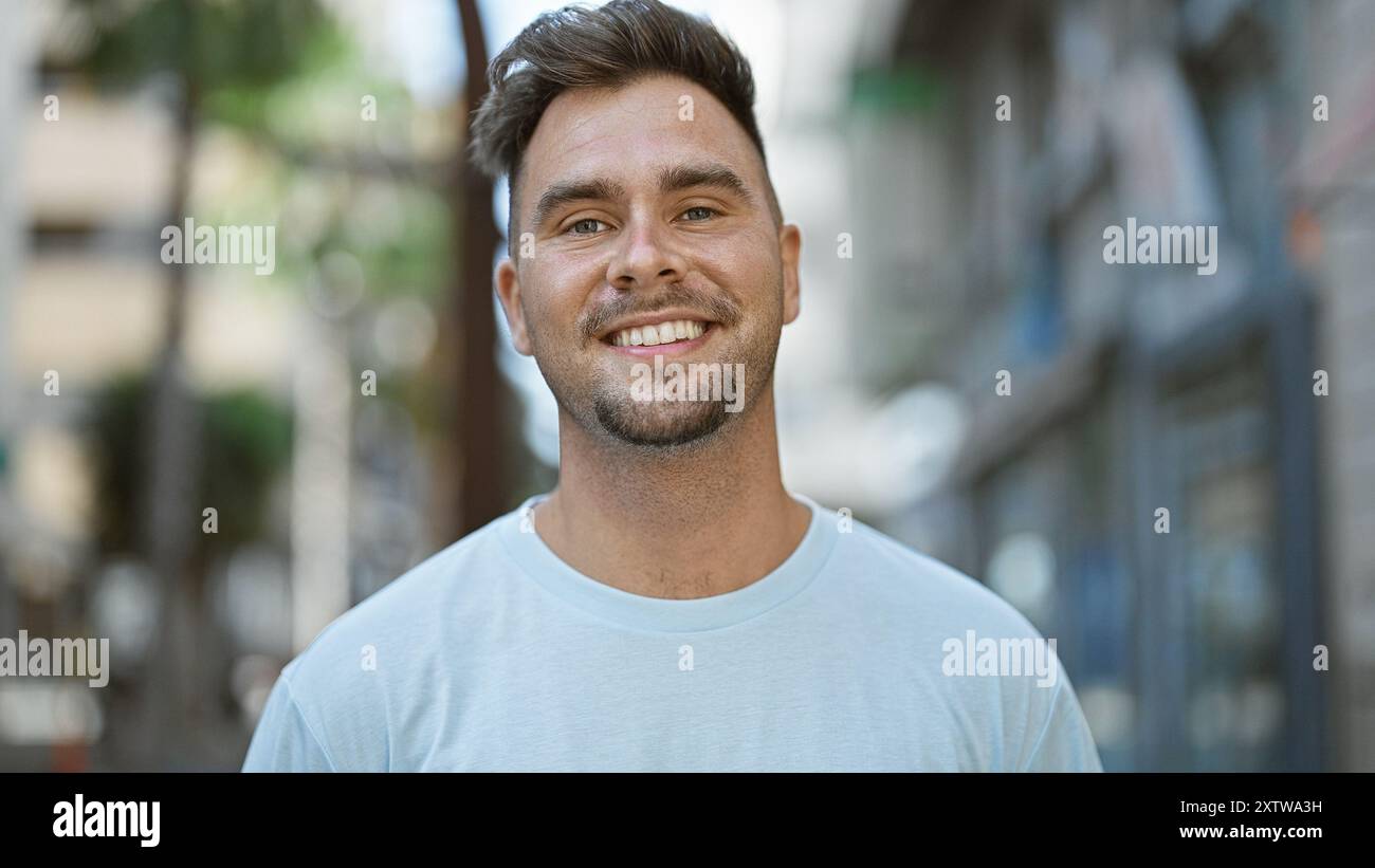 A handsome young hispanic man with a beard smiles joyfully on an urban ...
