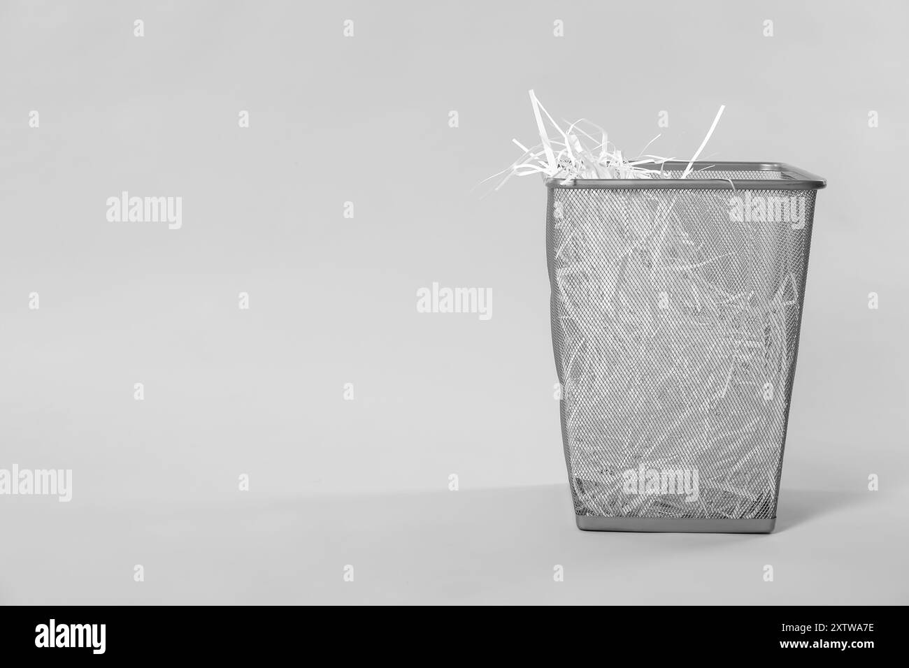 Shredded paper strips in trash bin on light grey background, space for ...