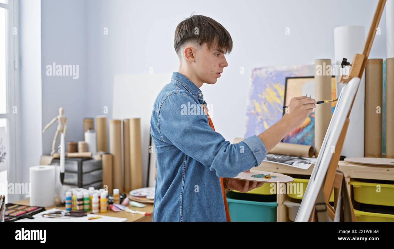 Caucasian teenage boy painting on canvas in art studio, showcasing ...