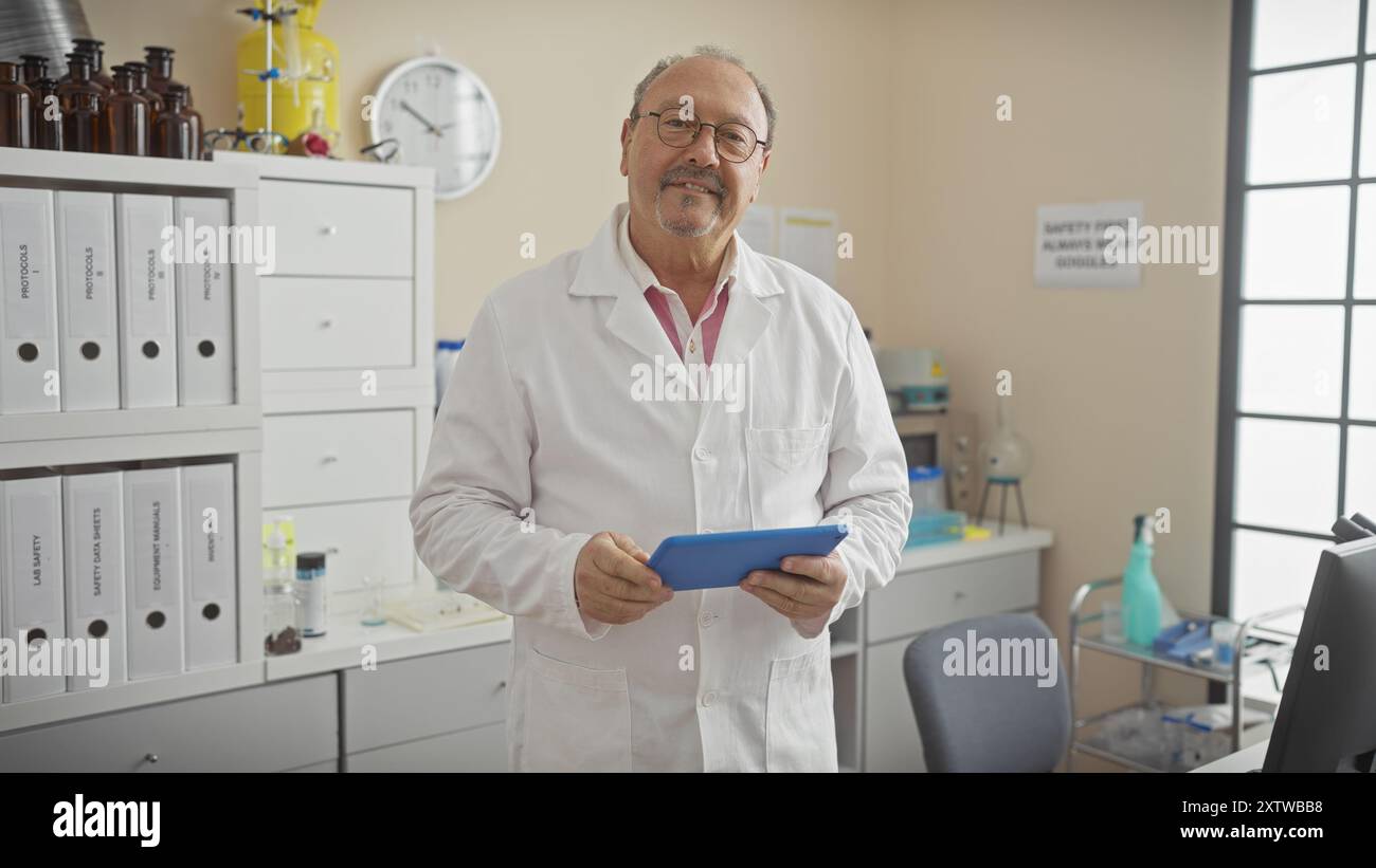 Mature man in labcoat holding tablet in laboratory setting with ...