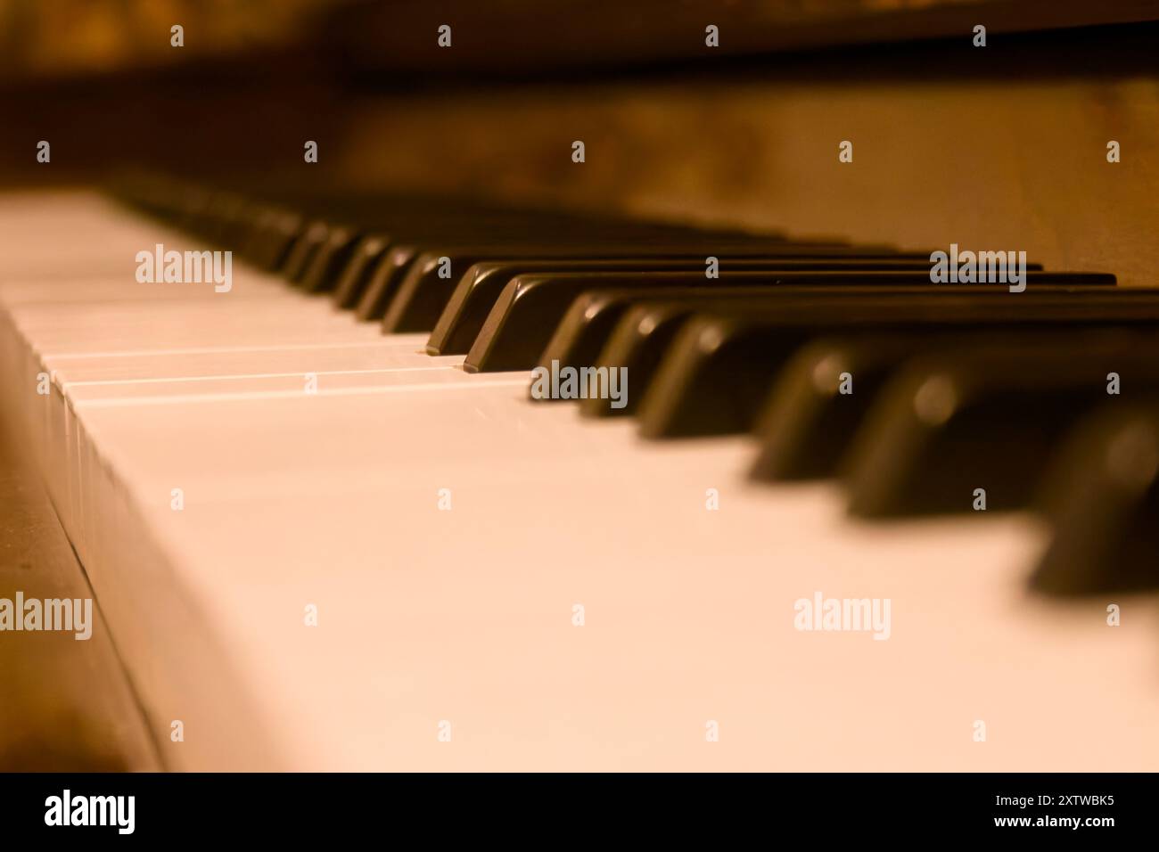 Close up of piano keyboard side view against bright orange background ...
