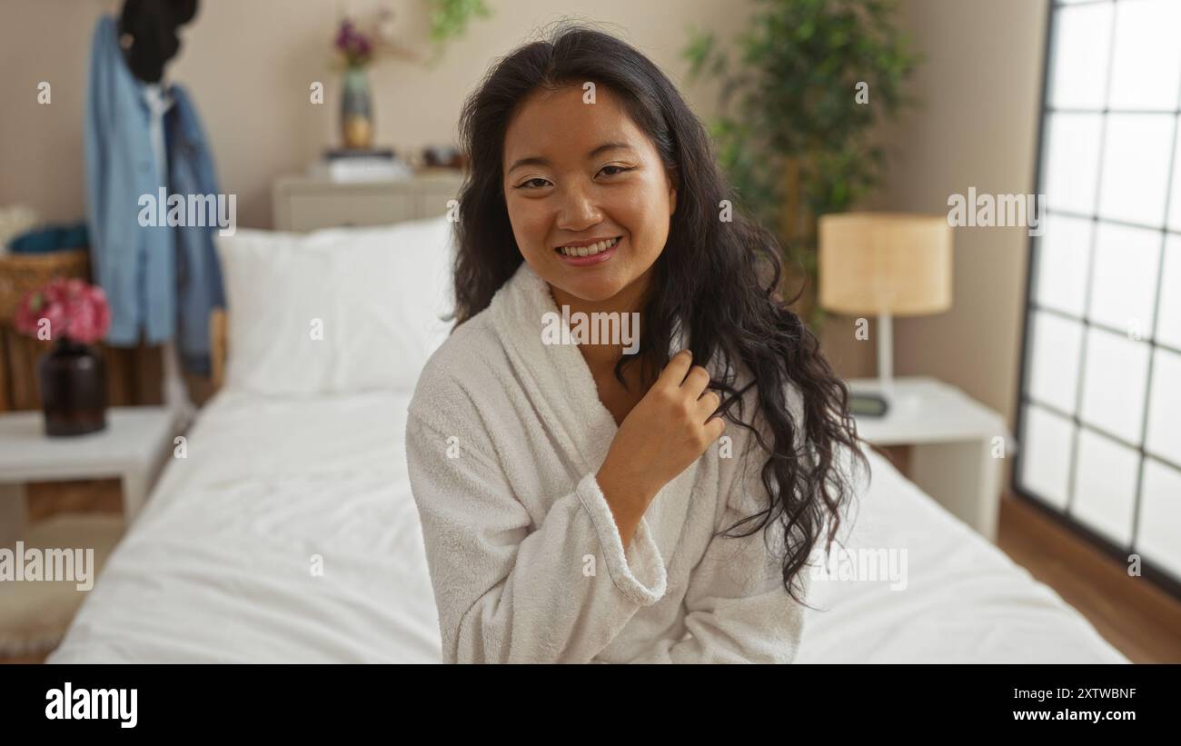 Beautiful young woman in a bedroom setting, sitting on a bed wearing a ...