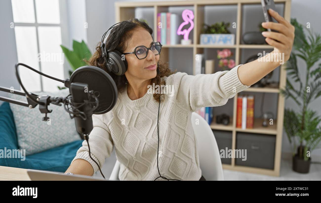 Smiling woman taking selfie in radio studio with microphone and ...