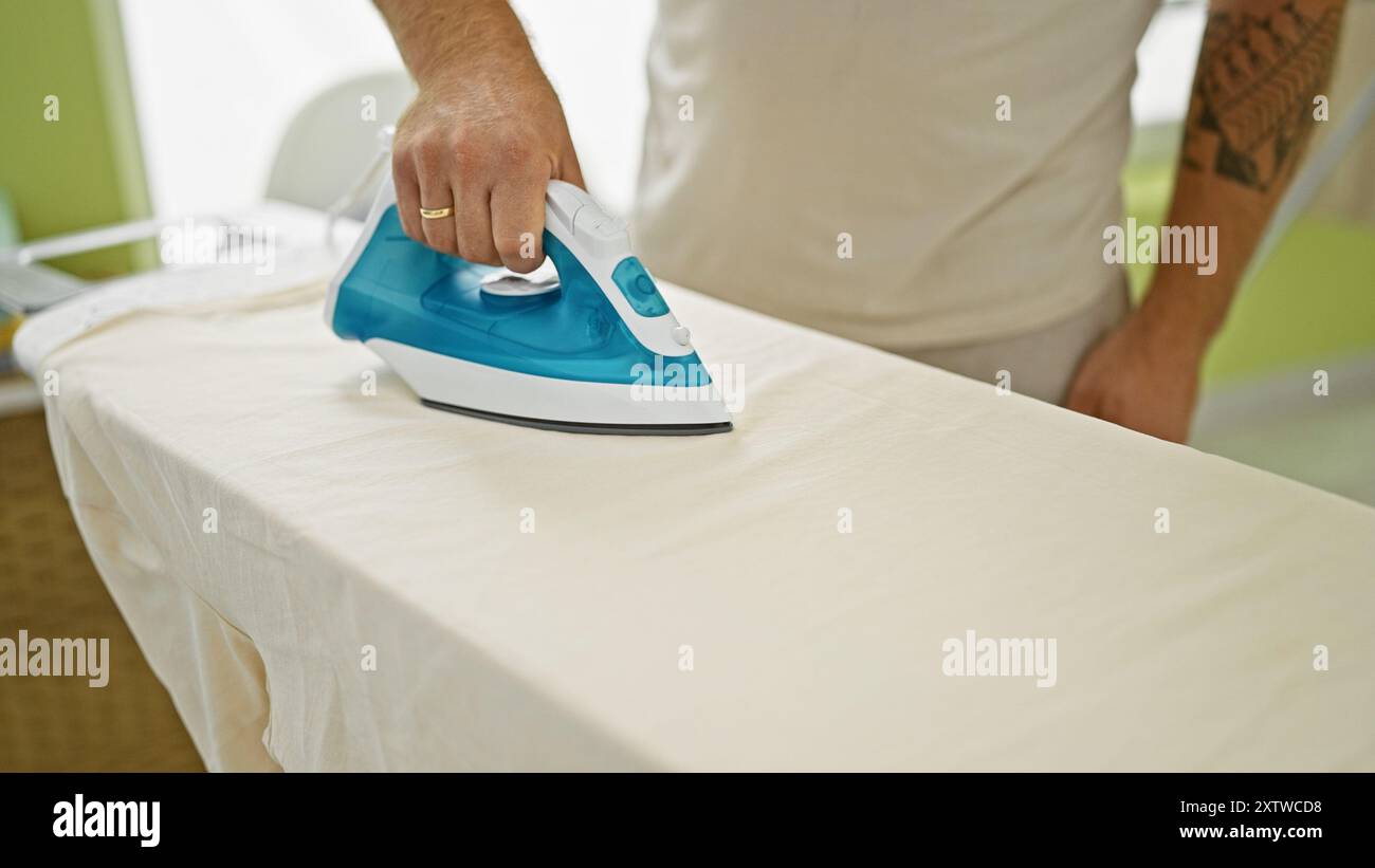 Man ironing clothes in a laundry room, capturing domestic chores with a ...