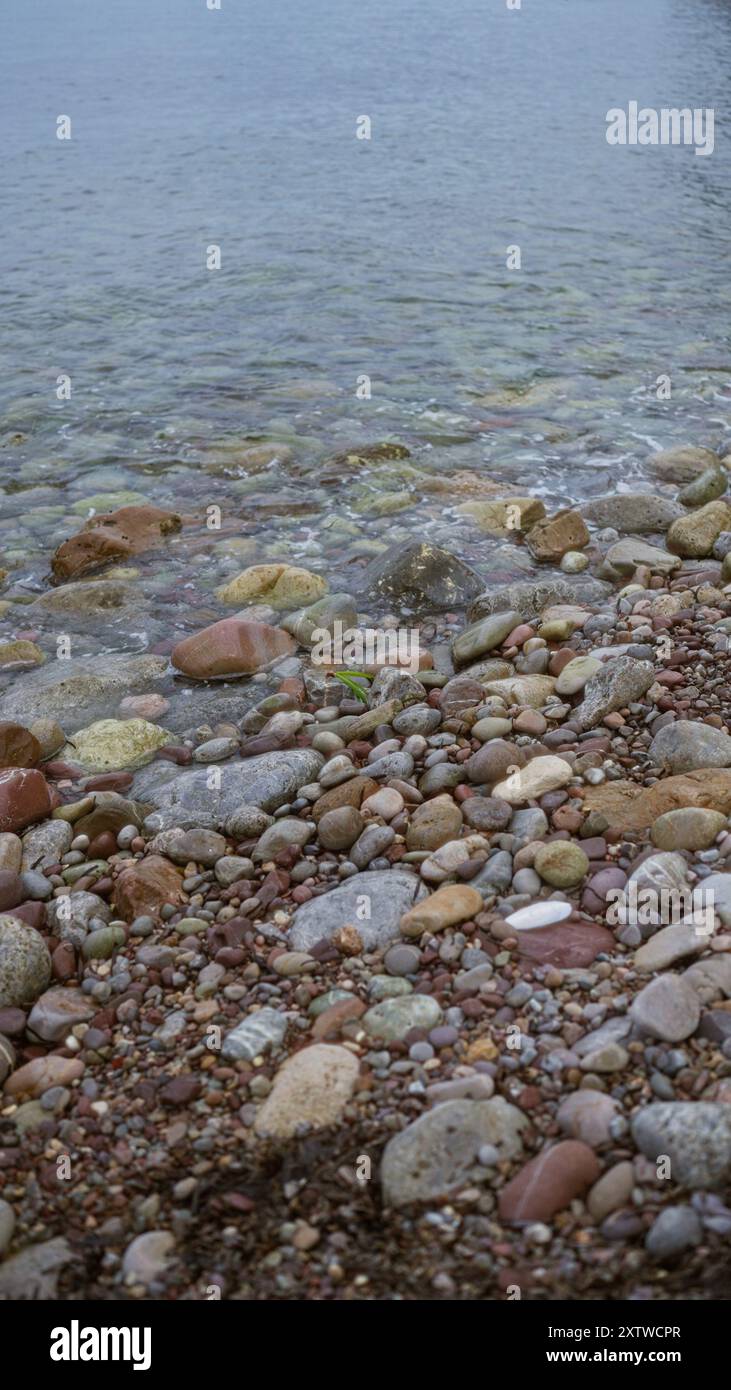 Rocky beach shoreline with pebbles and stones leading into translucent ...